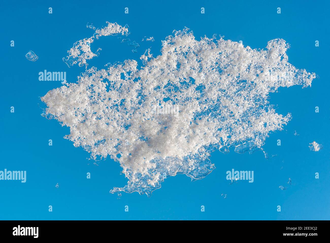 Snow on window glass, in winter, with a clear blue sky in background ...
