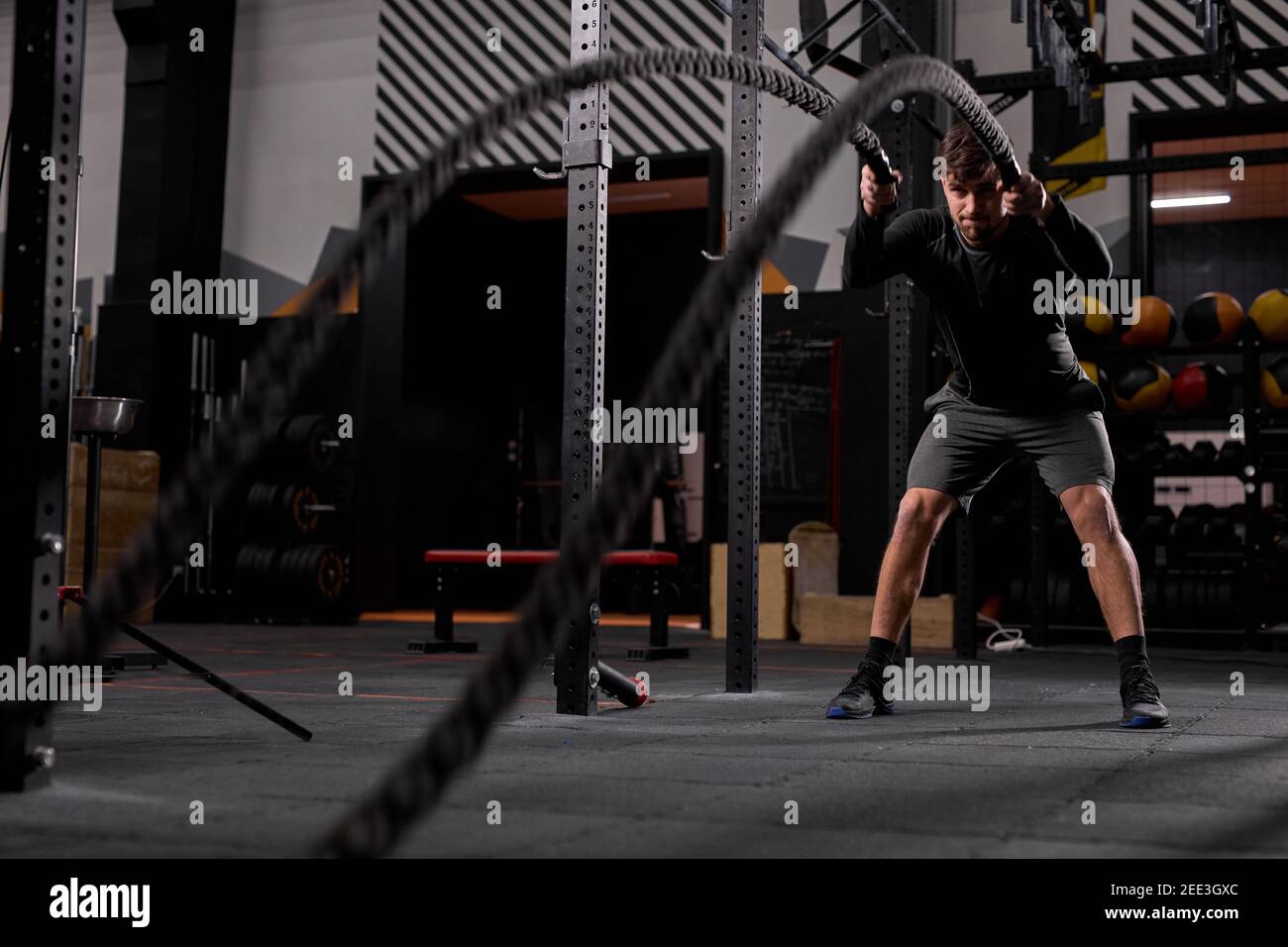 Athlete man training with rope, cross fit battle ropes exercise alone ...
