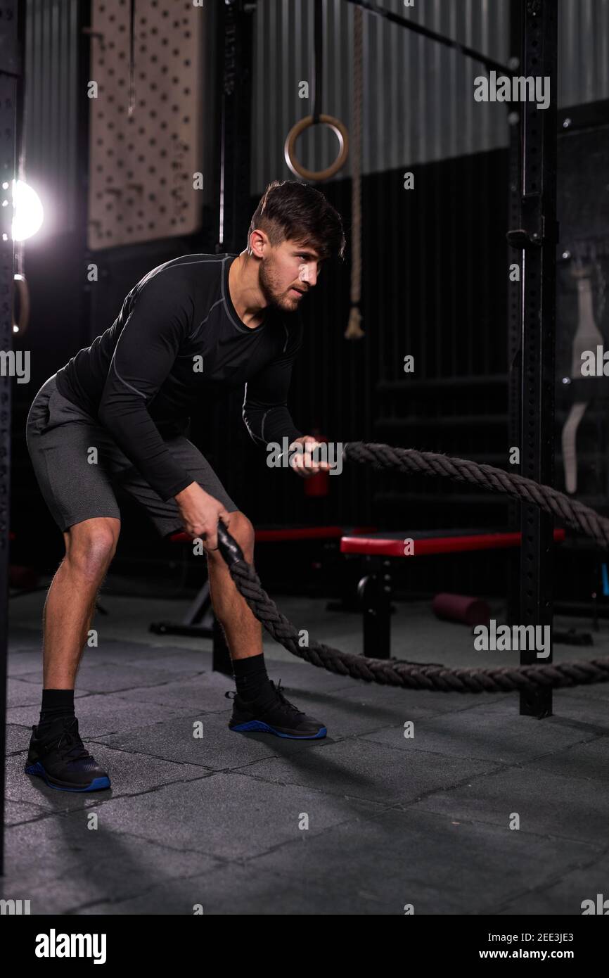 Athlete man training with rope, cross fit battle ropes exercise alone ...