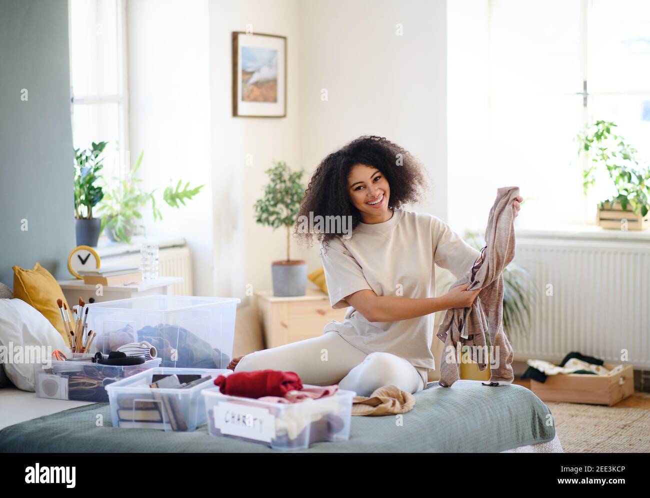 Young woman sorting clothing indoors at home, charity donation concept ...