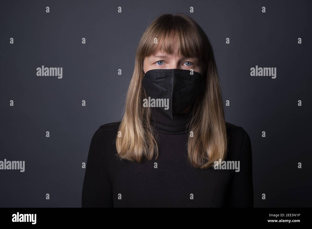 Blonde female in a black protective face mask with a sad tired ...