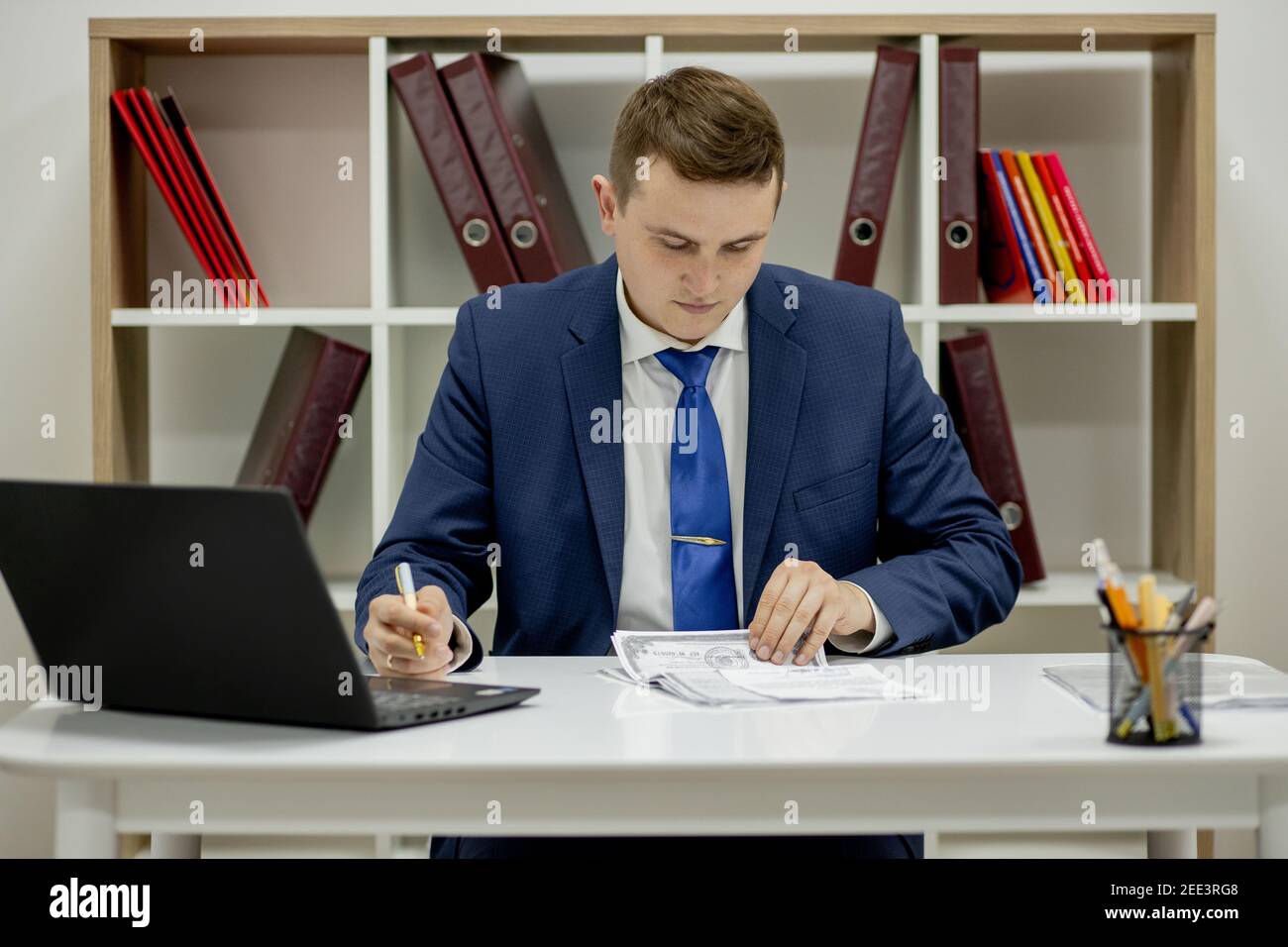 Young businessman working with documents looking through papers in ...