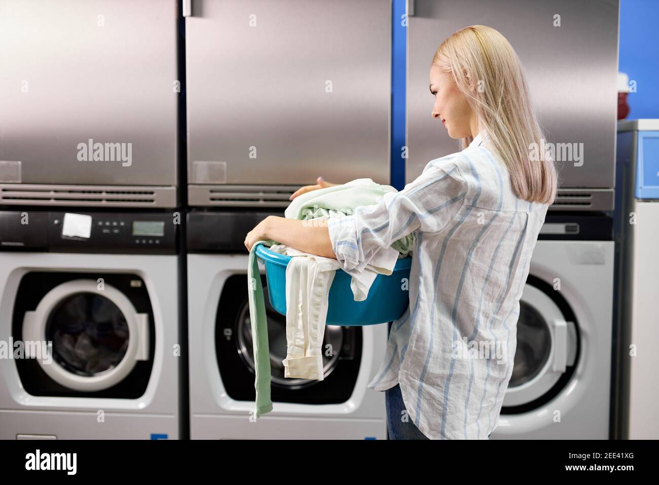 rear view on woman came to put clothes to wash in washing house, stand ...