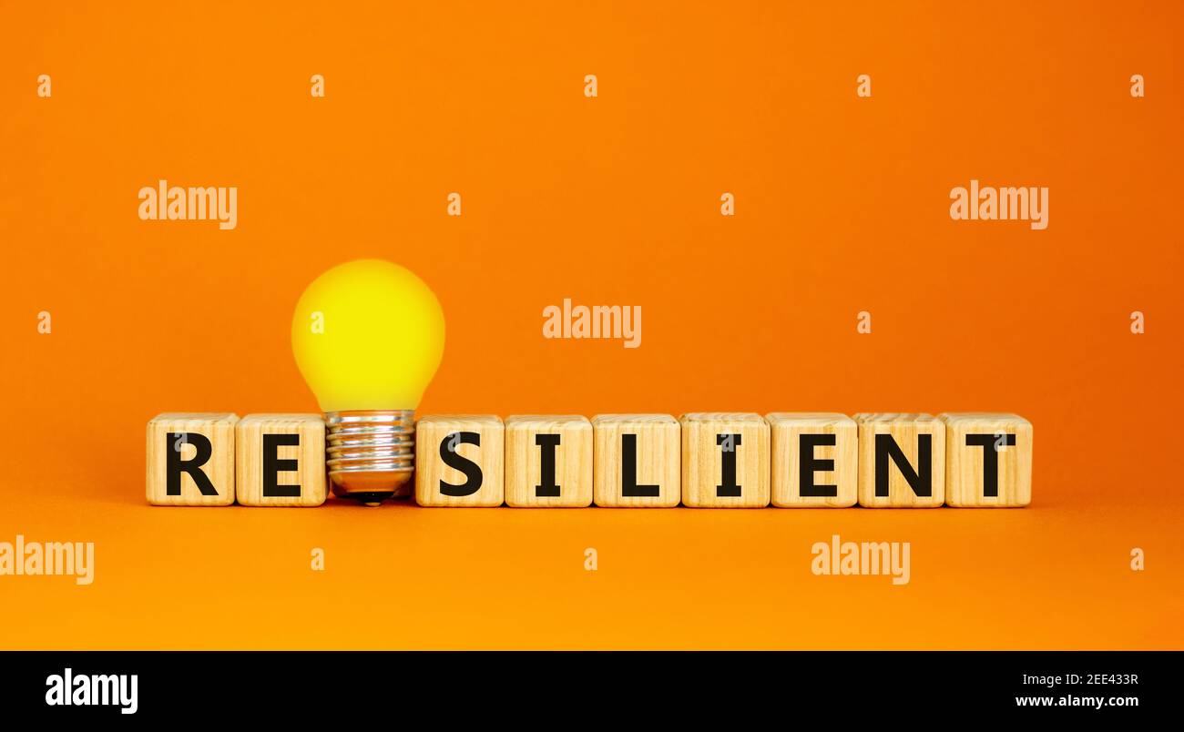 Resilient symbol. Wooden cubes with word 'resilient'. Yellow light bulb ...