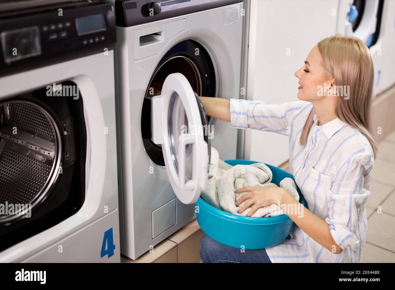 woman in washing house sorting clean clothes, doing household duties ...