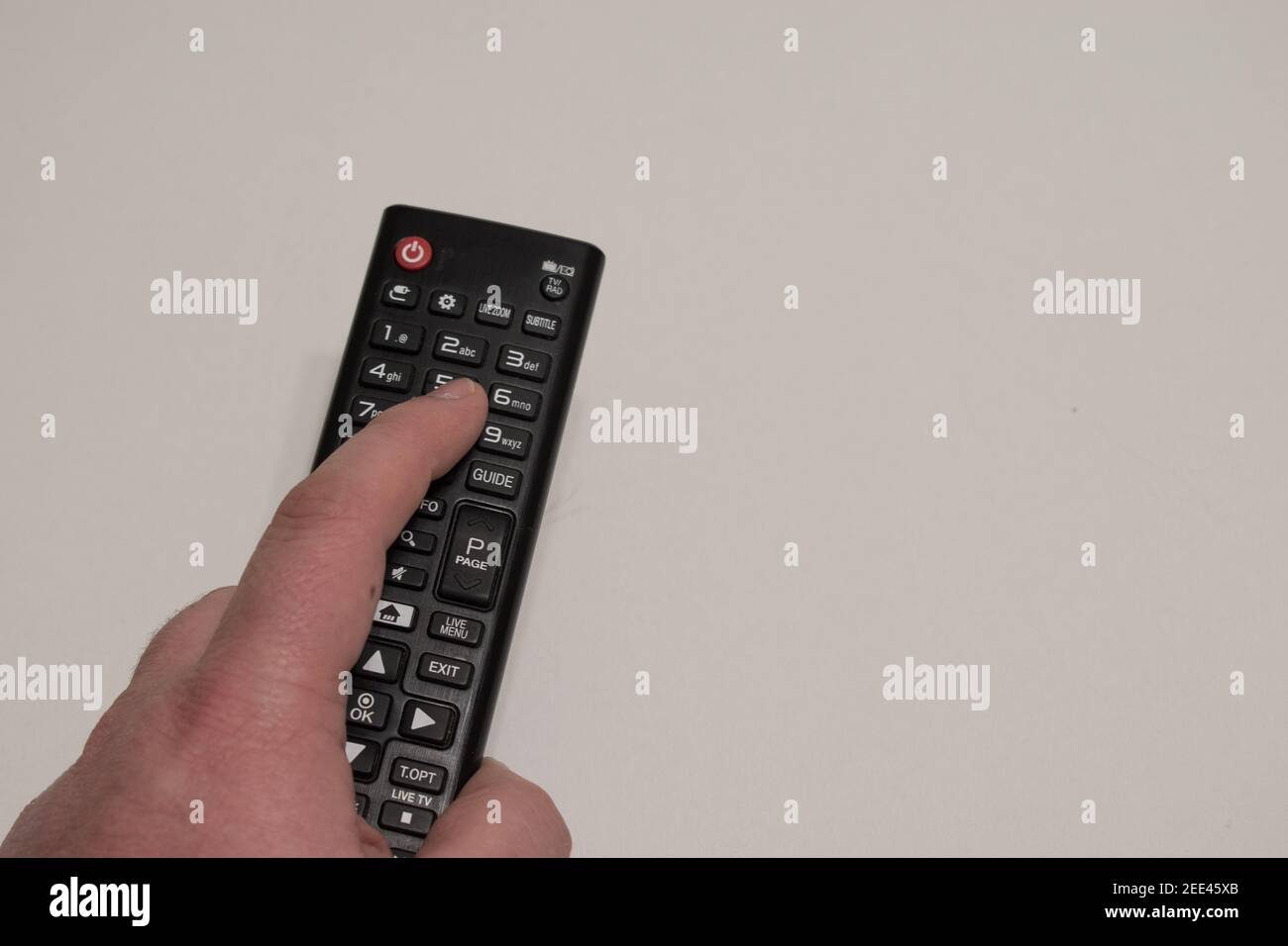 Hand holding black multimedia tv remote control on yellow background ...