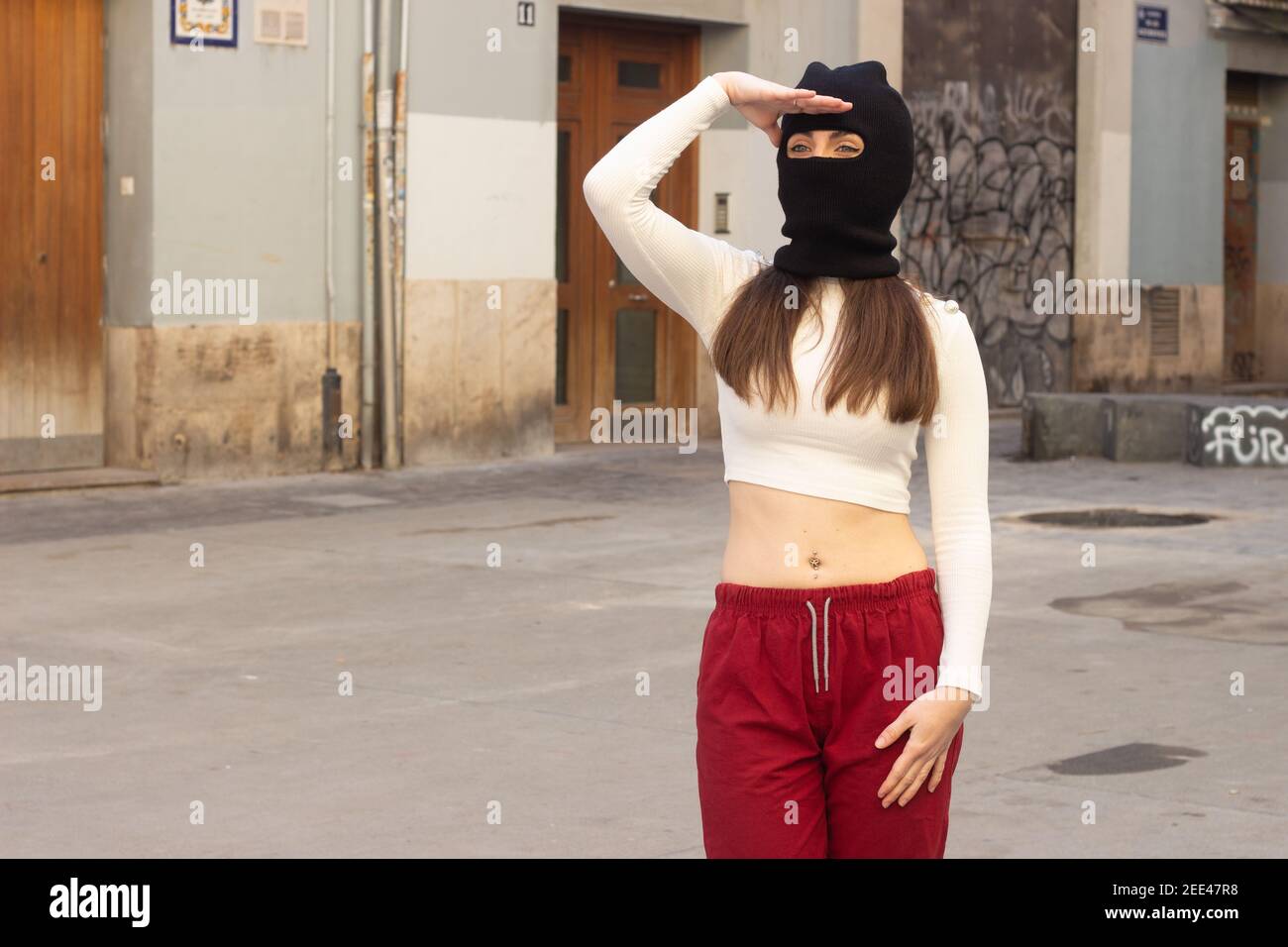 Criminal woman with a mask shading her eyes with a hand and looking ...