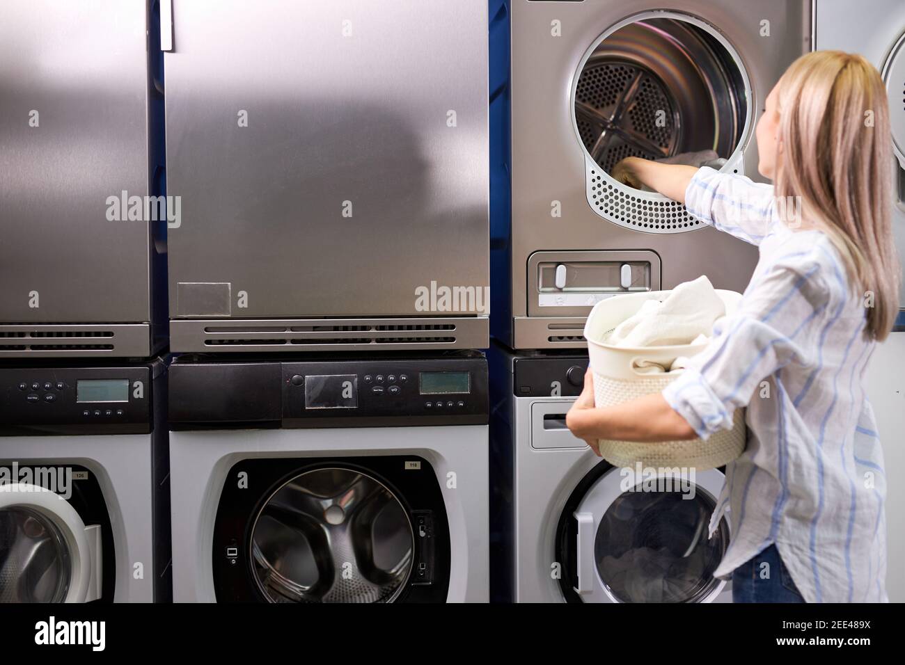 Housework: young woman doing laundry - putting white garments into the ...