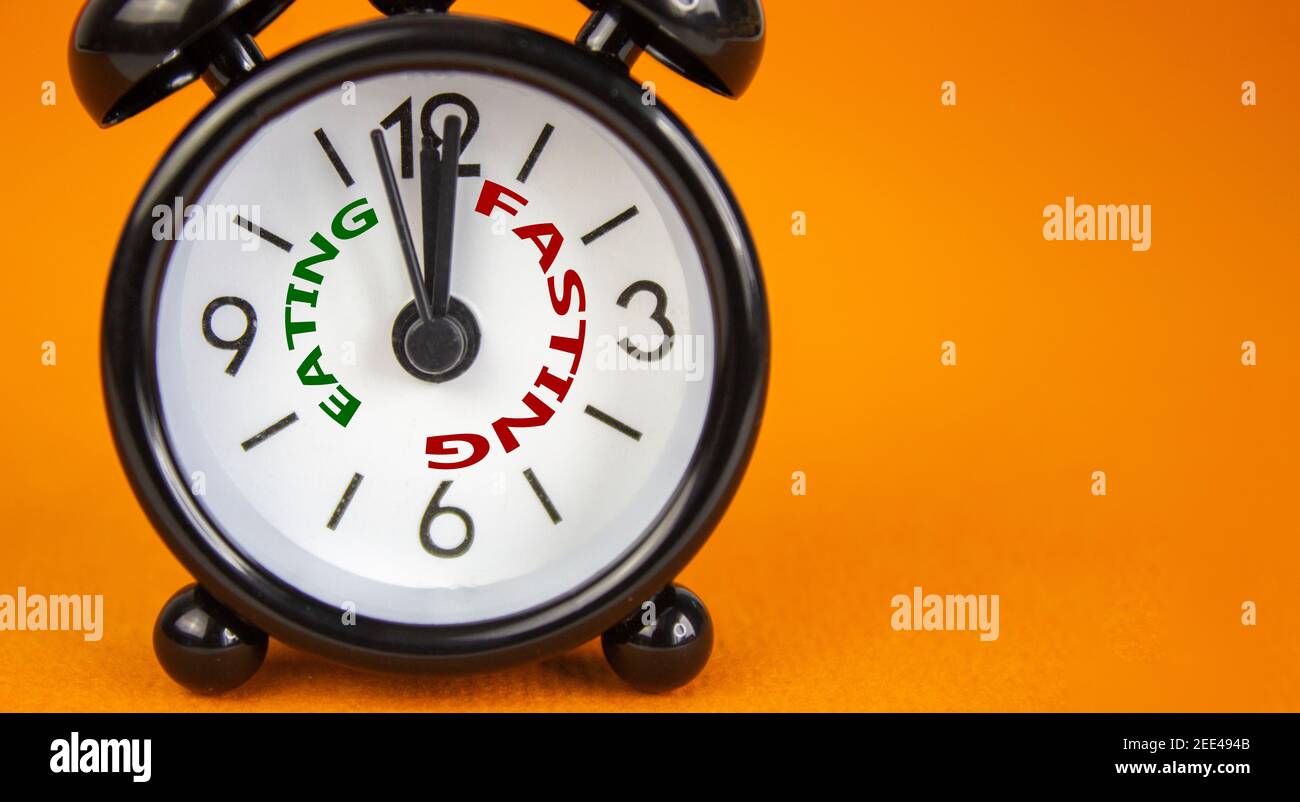 Time to fasting symbol. Beautiful black alarm clock with words 'eating ...