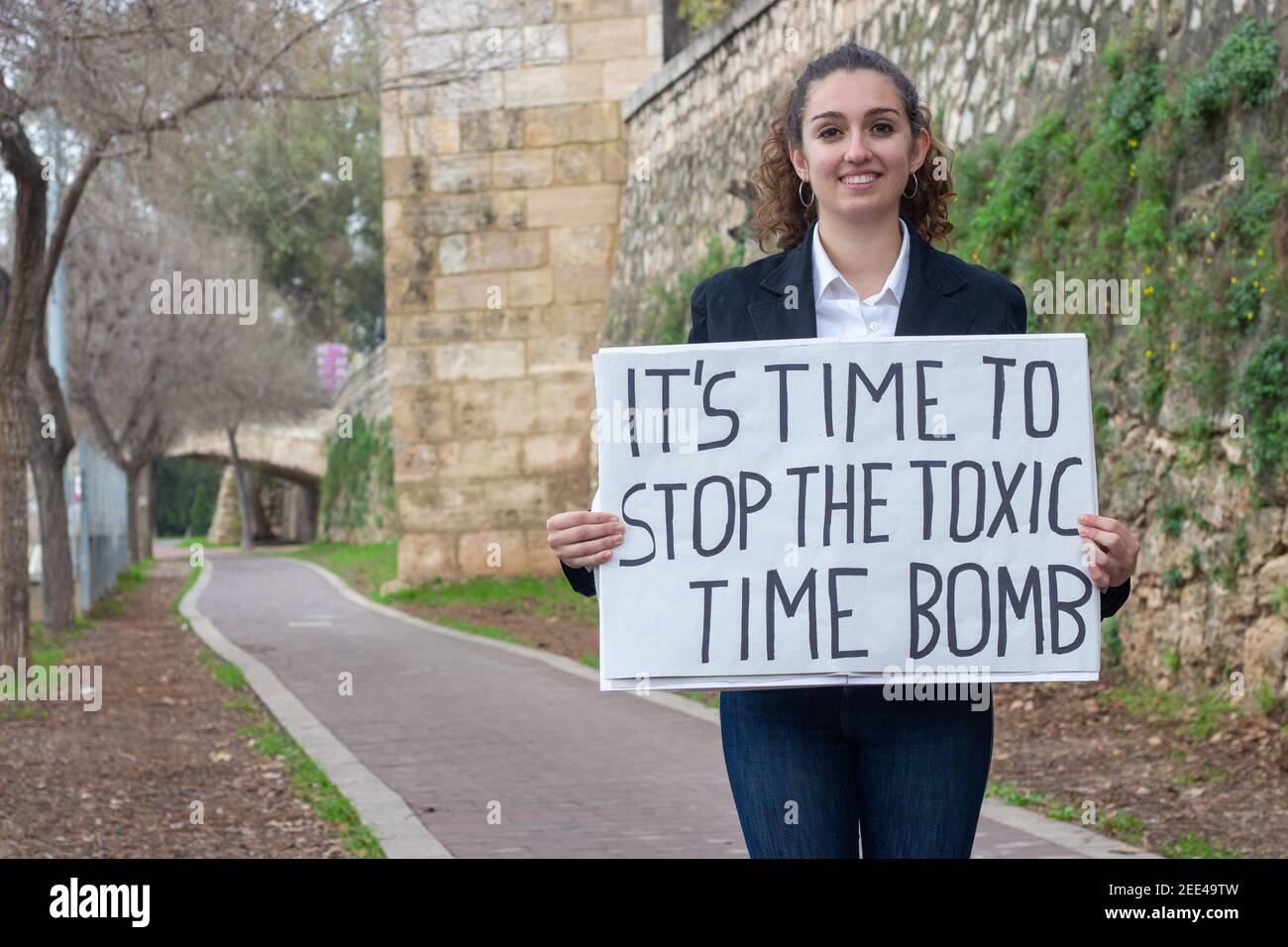 Smiling activist woman holding an "IT'S TIME TO STOP THE TOXIC TIME ...
