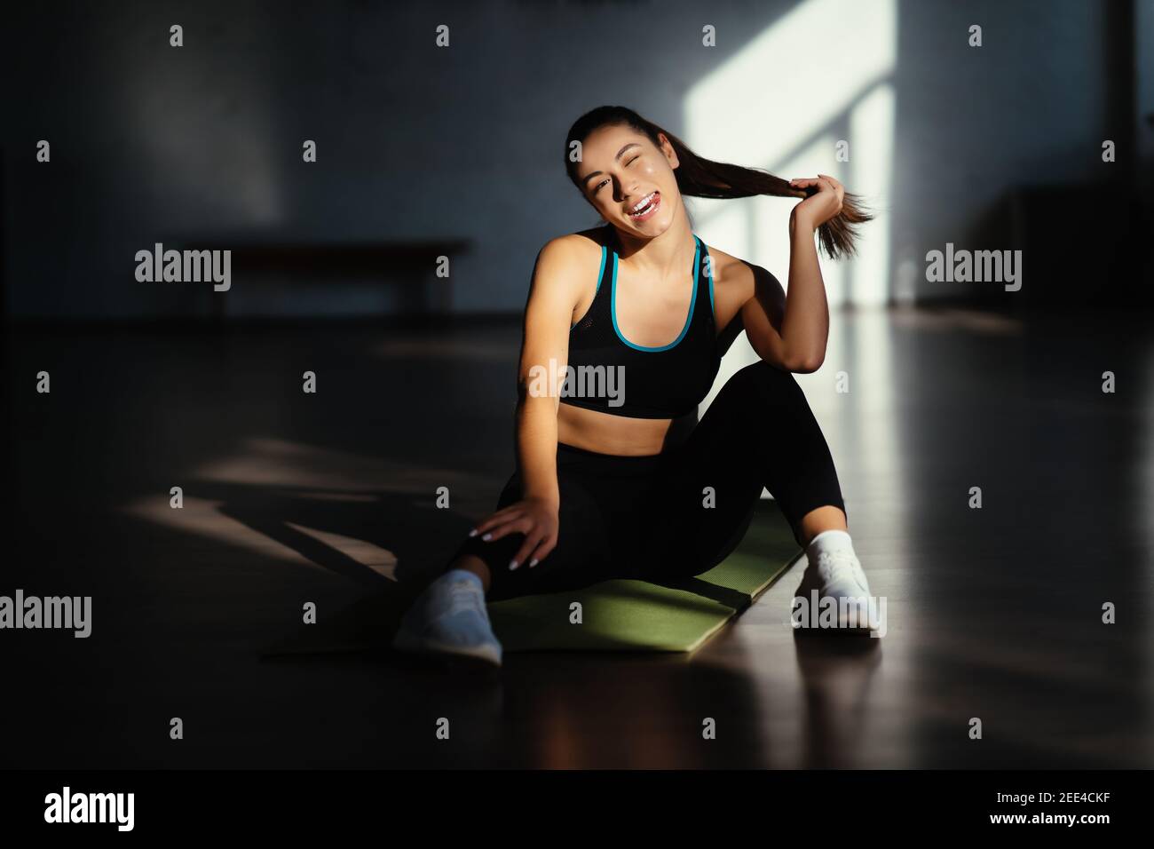 Fit woman resting after home workout, sitting on mat Stock Photo - Alamy