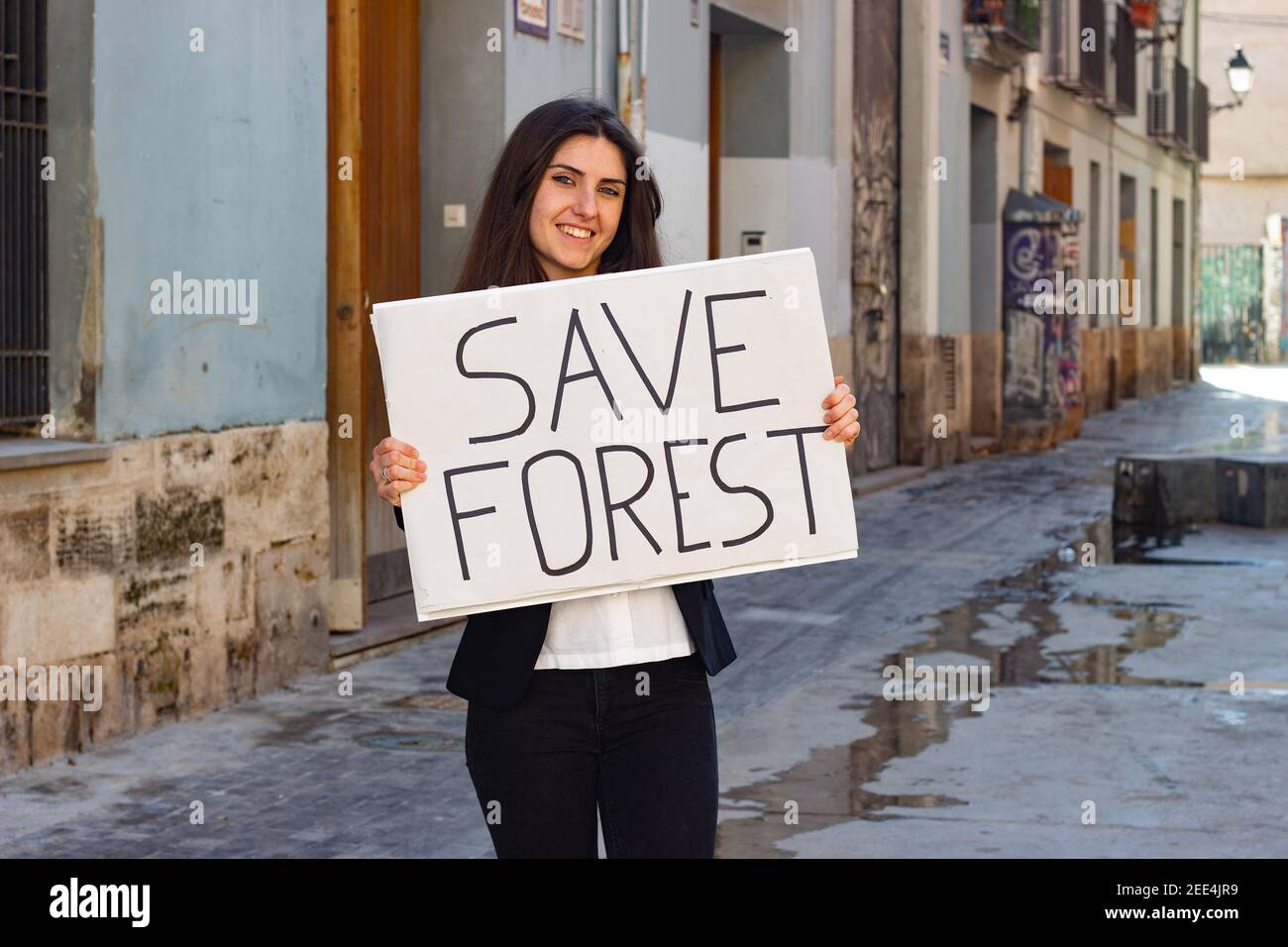Shallow focus of a female environmental activist holding a "SAVE FOREST ...