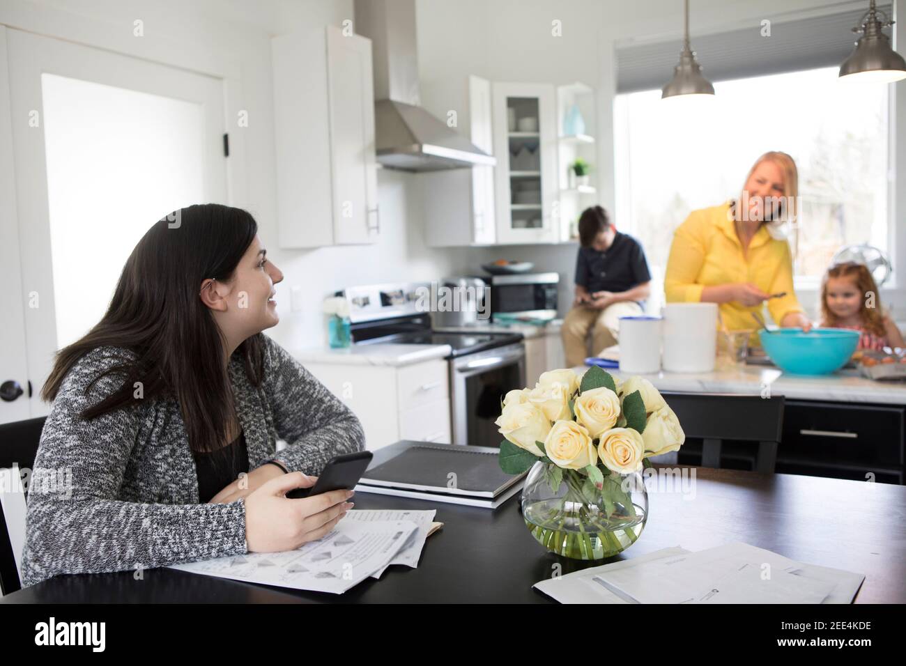 A mom talks to her teenage daughter in the kitchen while baking with ...