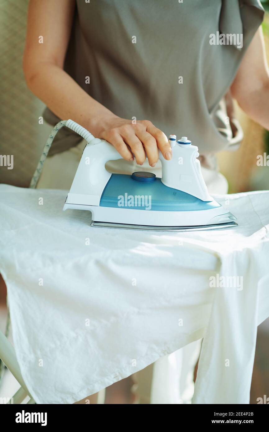 Closeup on female in the house in sunny day ironing on ironing board ...