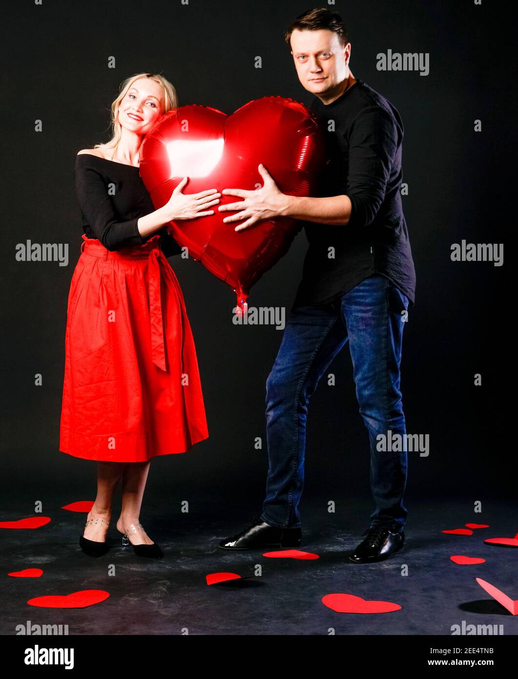 A girl and a guy hold a heart balloon inflatable love symbol, happiness ...
