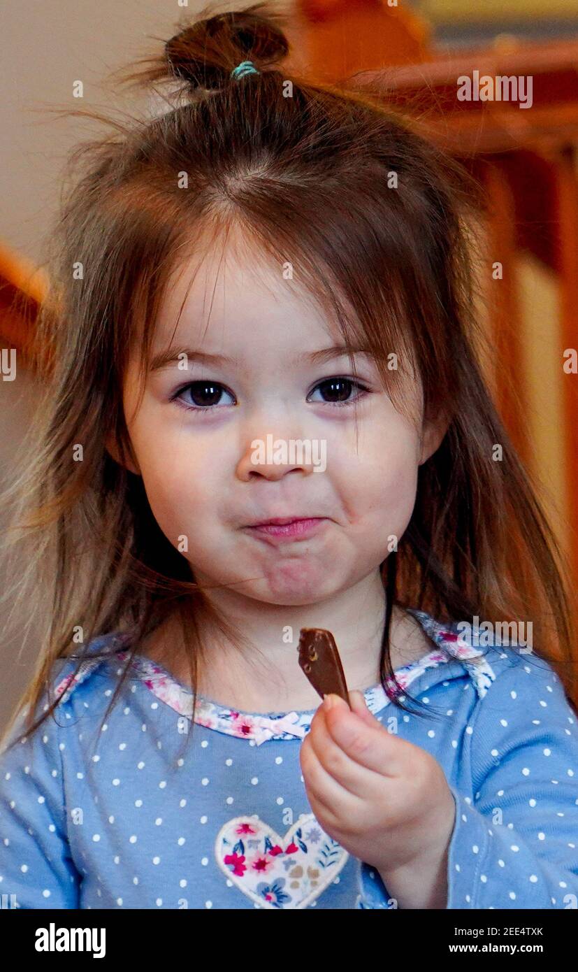 Cheeky face enjoys her chocolate candy Stock Photo - Alamy