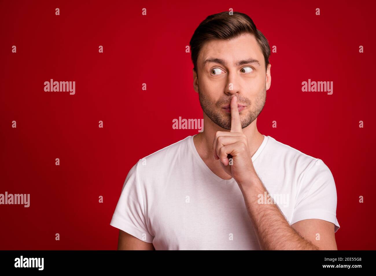 Portrait of handsome guy finger covering lips do not tell look empty ...