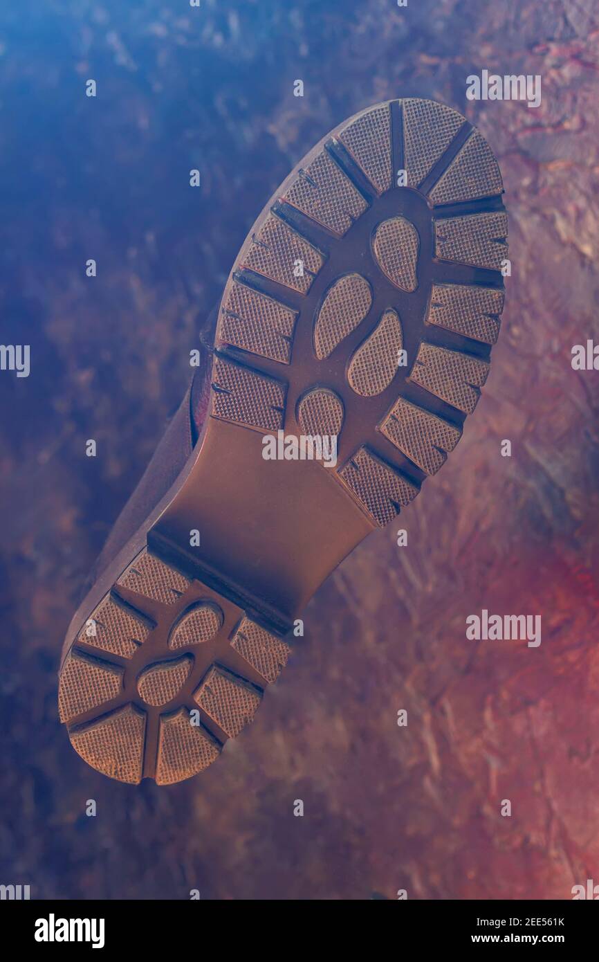 Dirty boot sole close-up on a two-tone gradient background, hiking ...