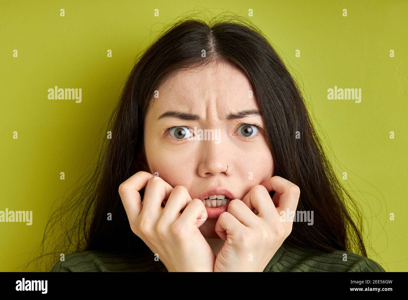 scared female standing in fear holding hands near face, looking at ...