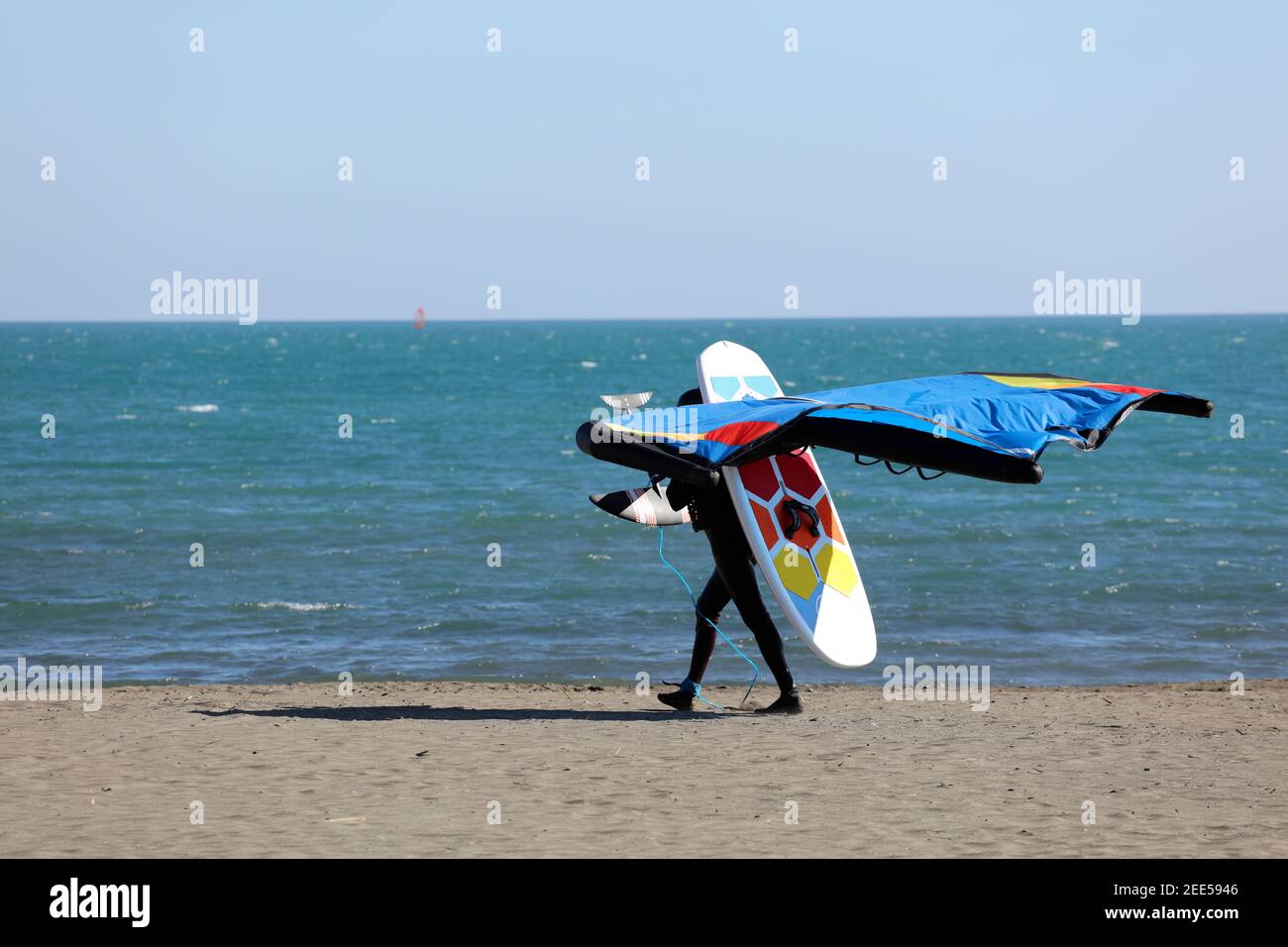 man walking on the beach with hydrofoil and paragliding, (wing-surfer ...