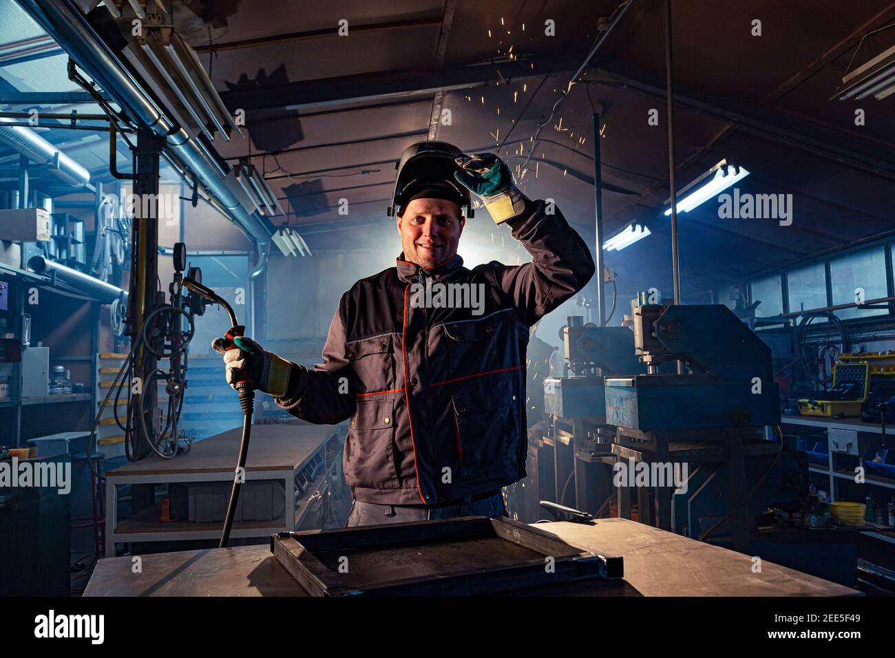 Portrait of a smiling welder posing at his workplace in the factory ...