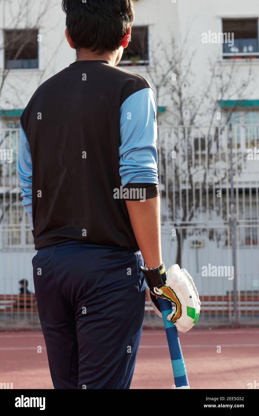 Cricket player from behind leaning on his bat Stock Photo - Alamy