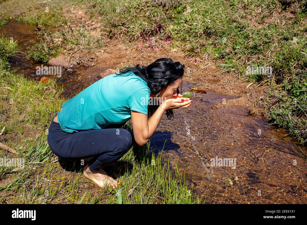 Woman drinking water in a crystal clear stream Stock Photo - Alamy
