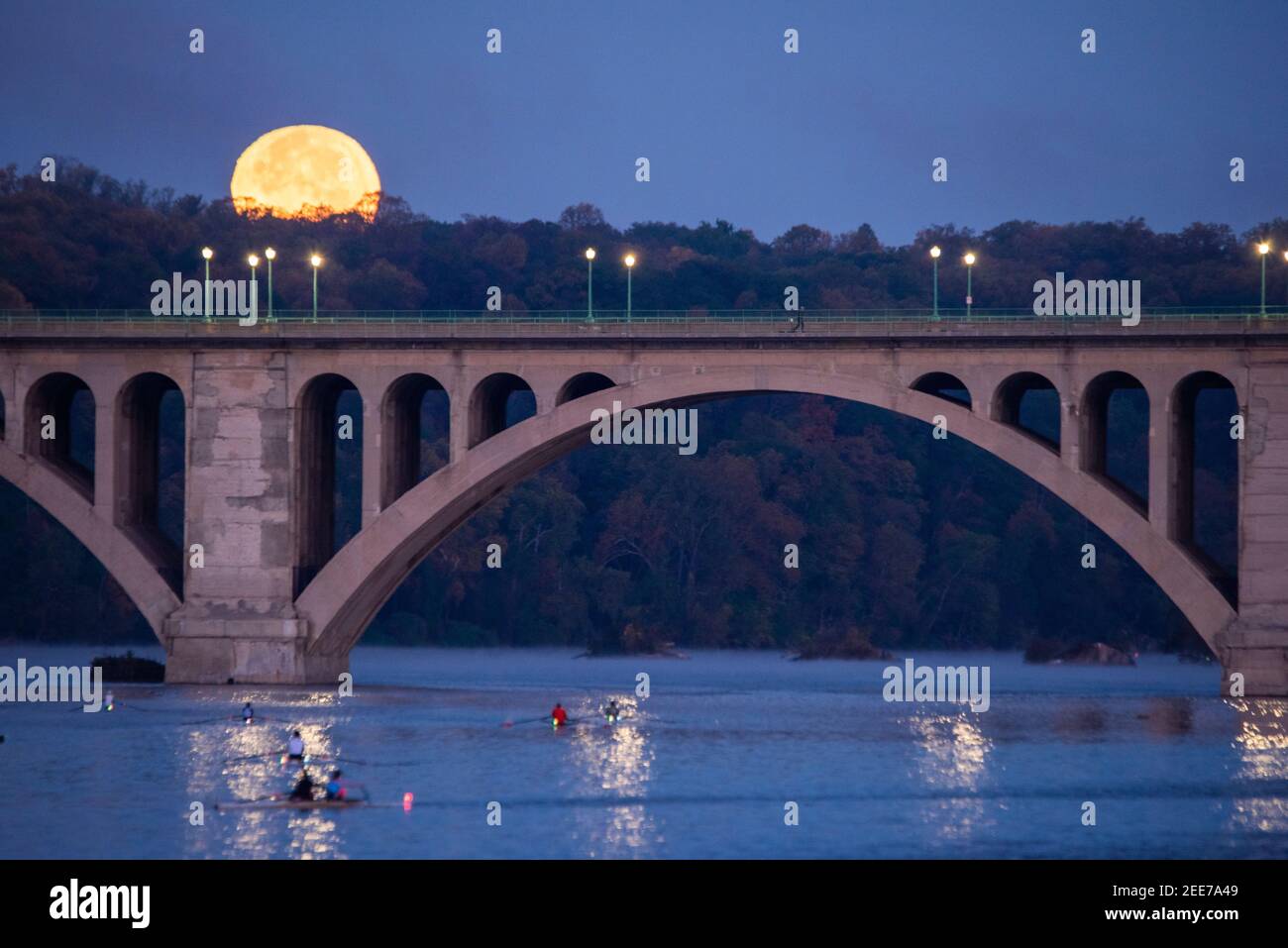 The full moon sets over the Potomac River and Key Bridge which connects ...