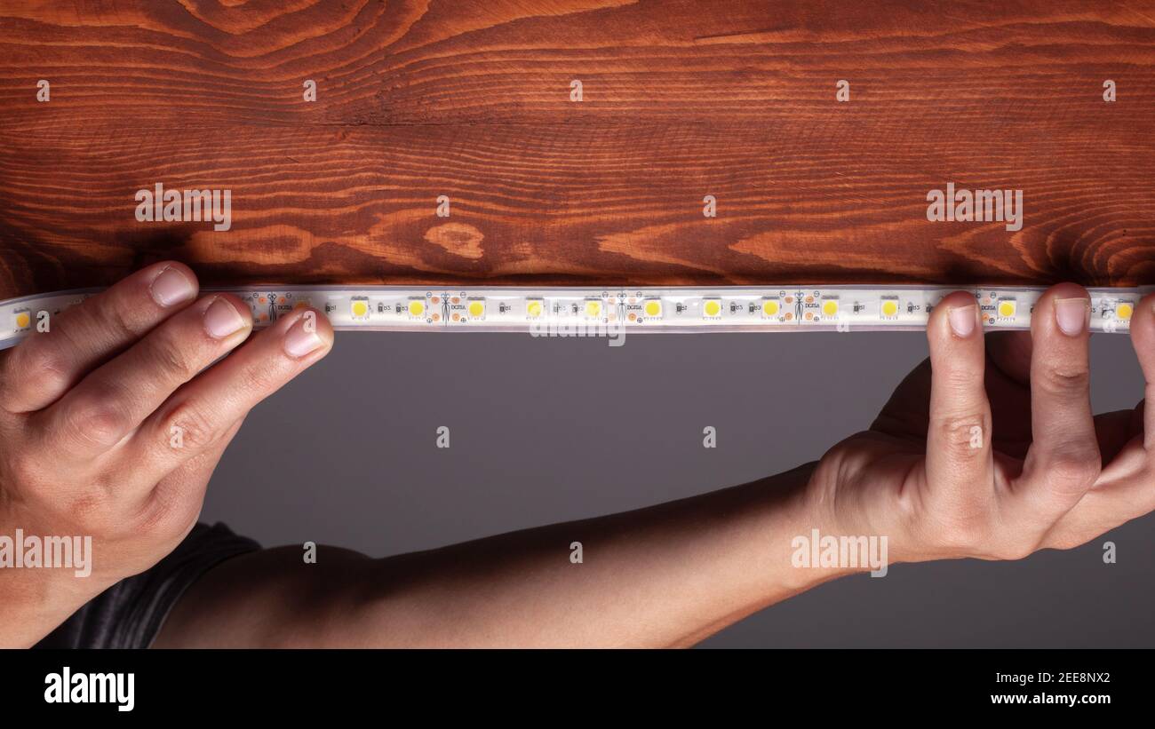 installing led strip lighting for under wooden table Stock Photo - Alamy