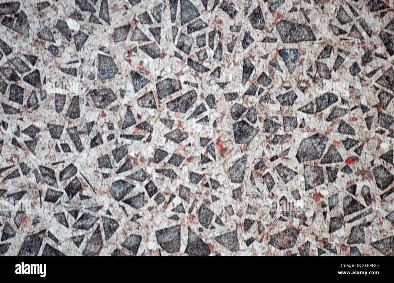 A fragment of a dark stone mosaic wall on a concrete screed. Background ...