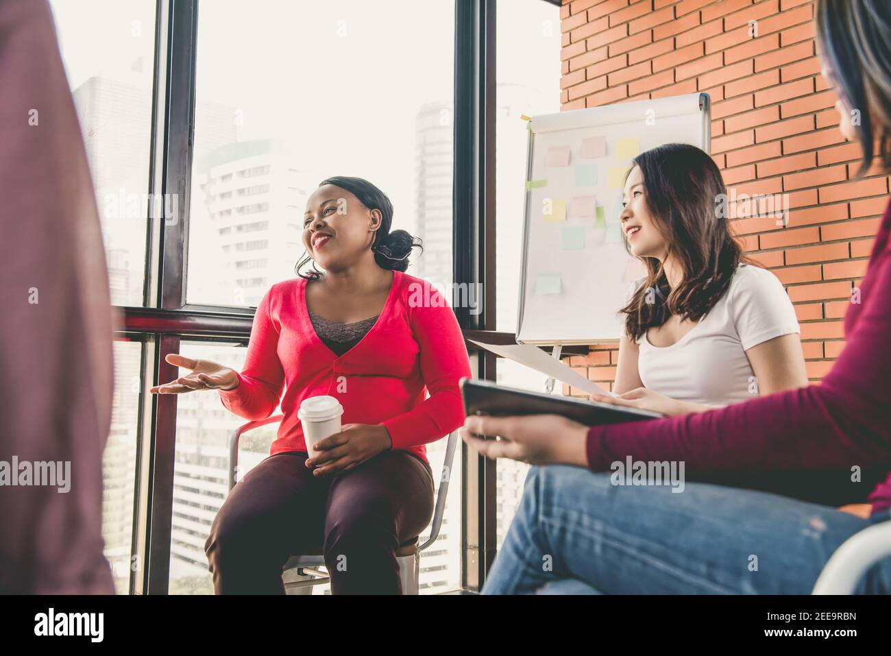 Diverse group of women in colorful clothes at the meeting, discussing ...
