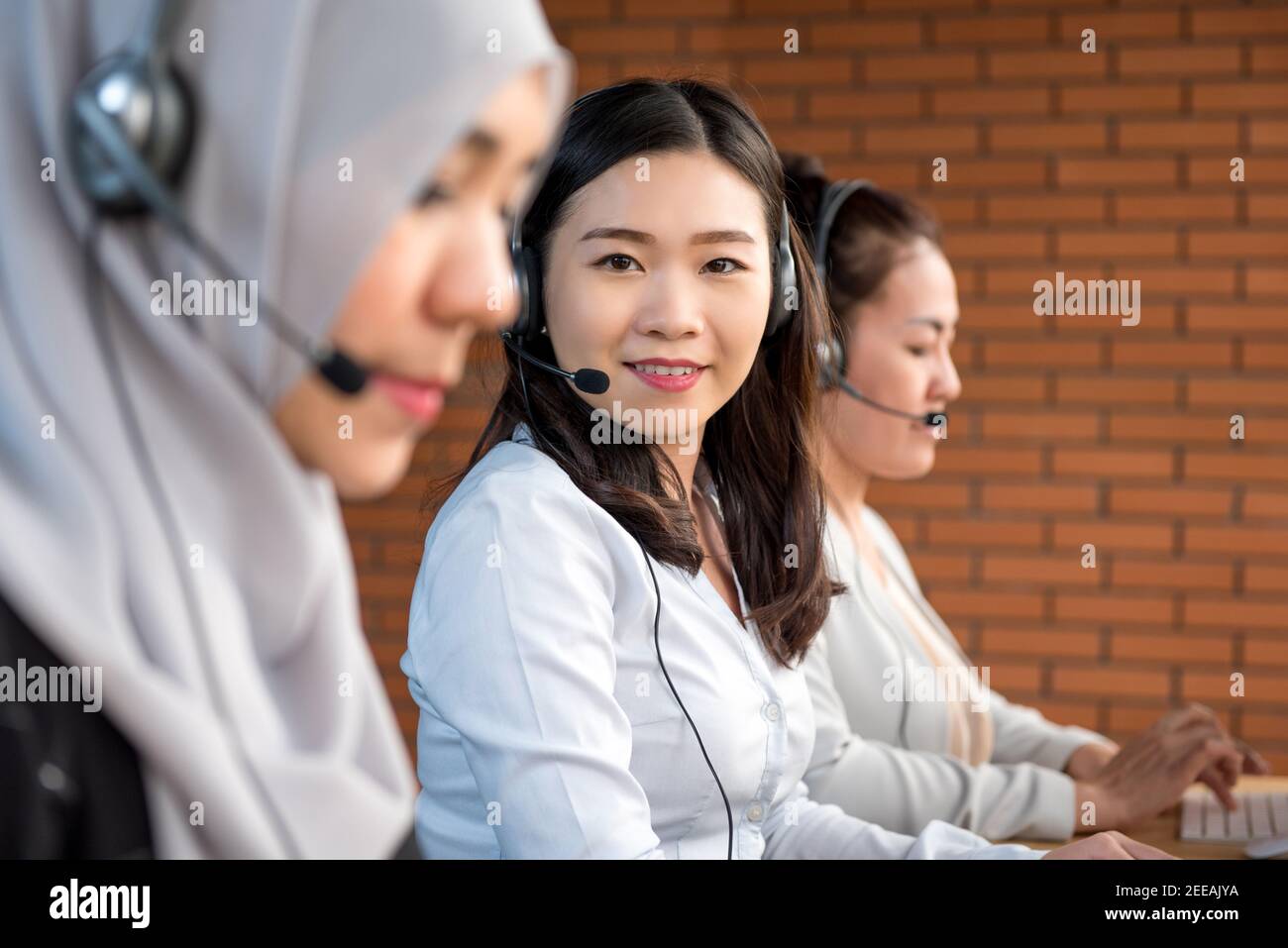 Mixed Asian woman team, Muslim Chinese and Japanese, working in call ...