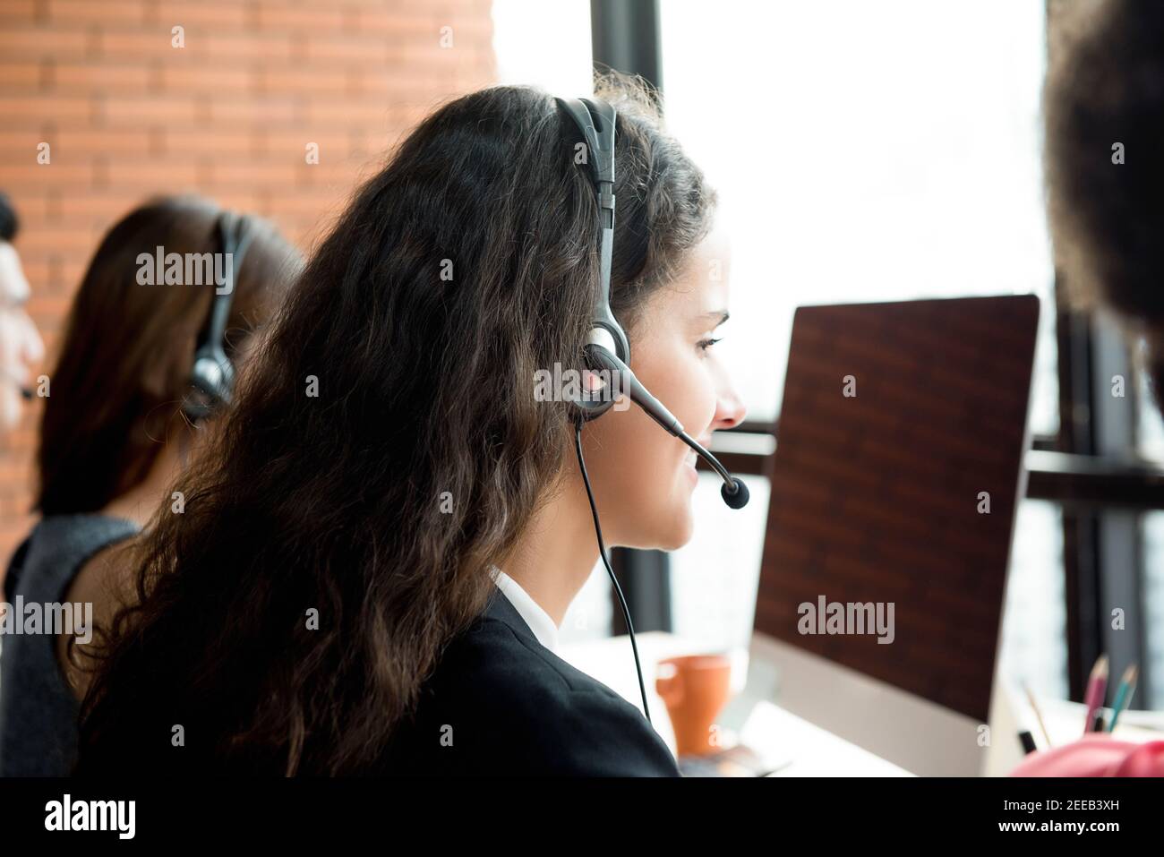 Back view of businesswomen wearing microphone headset working as a ...