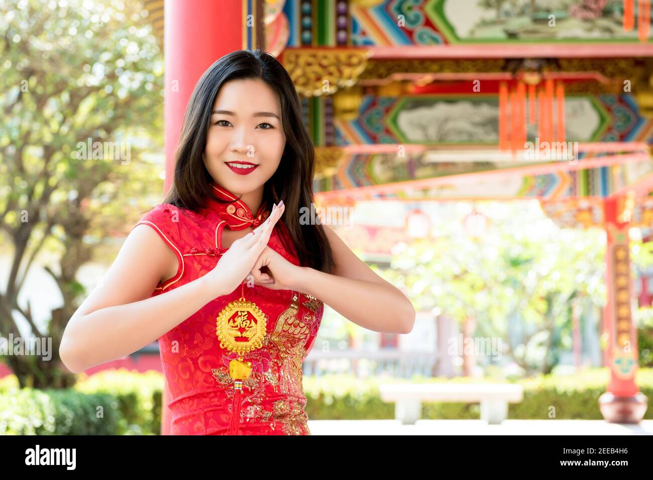 Smiling Asian woman in traditional red cheongsam qipao dress making ...