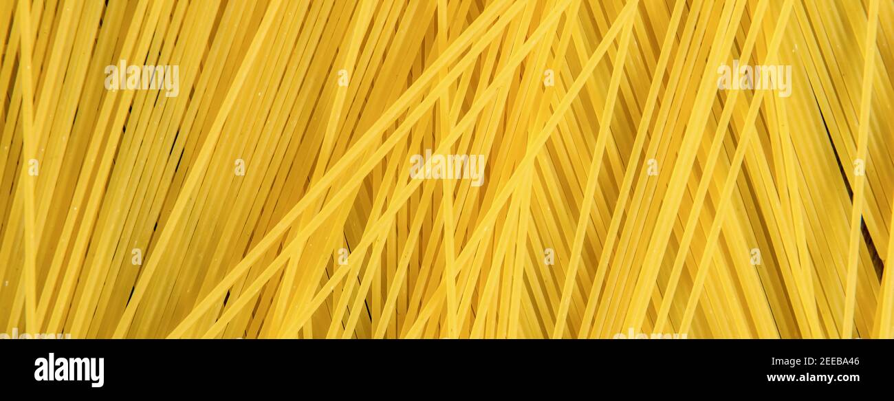 Yellow uncooked noodle raw spaghetti pasta top view, panoramic banner ...
