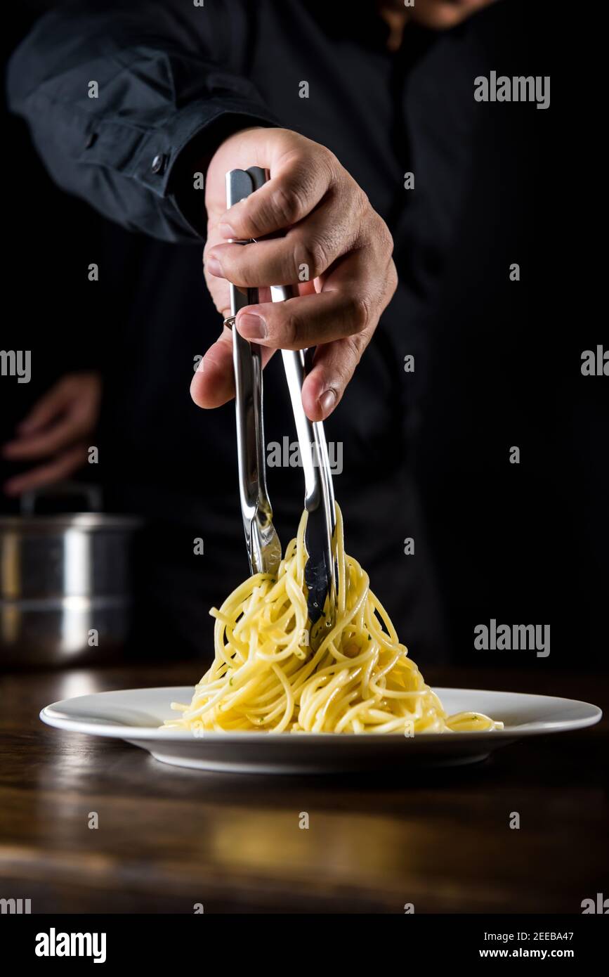 Traditional Italian spaghetti pasta being cooked and plated by chef at ...