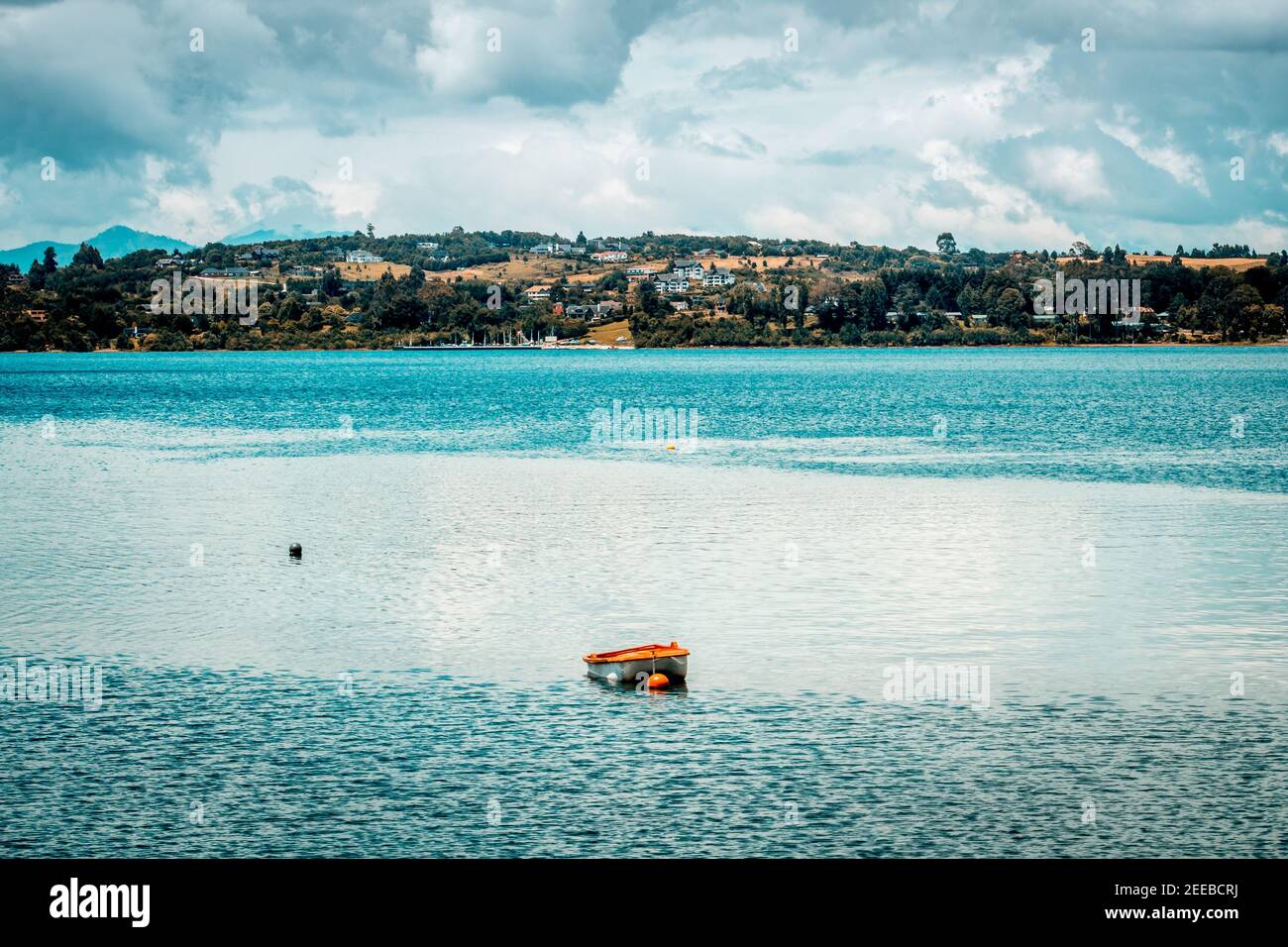 Empty floating boat on a calm sea with a village in an island ...