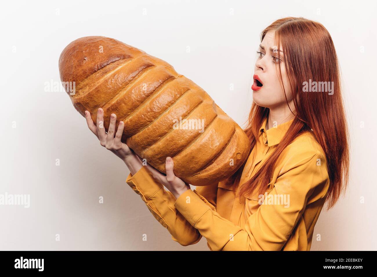emotional woman holding a loaf in a horizontal position on a light ...