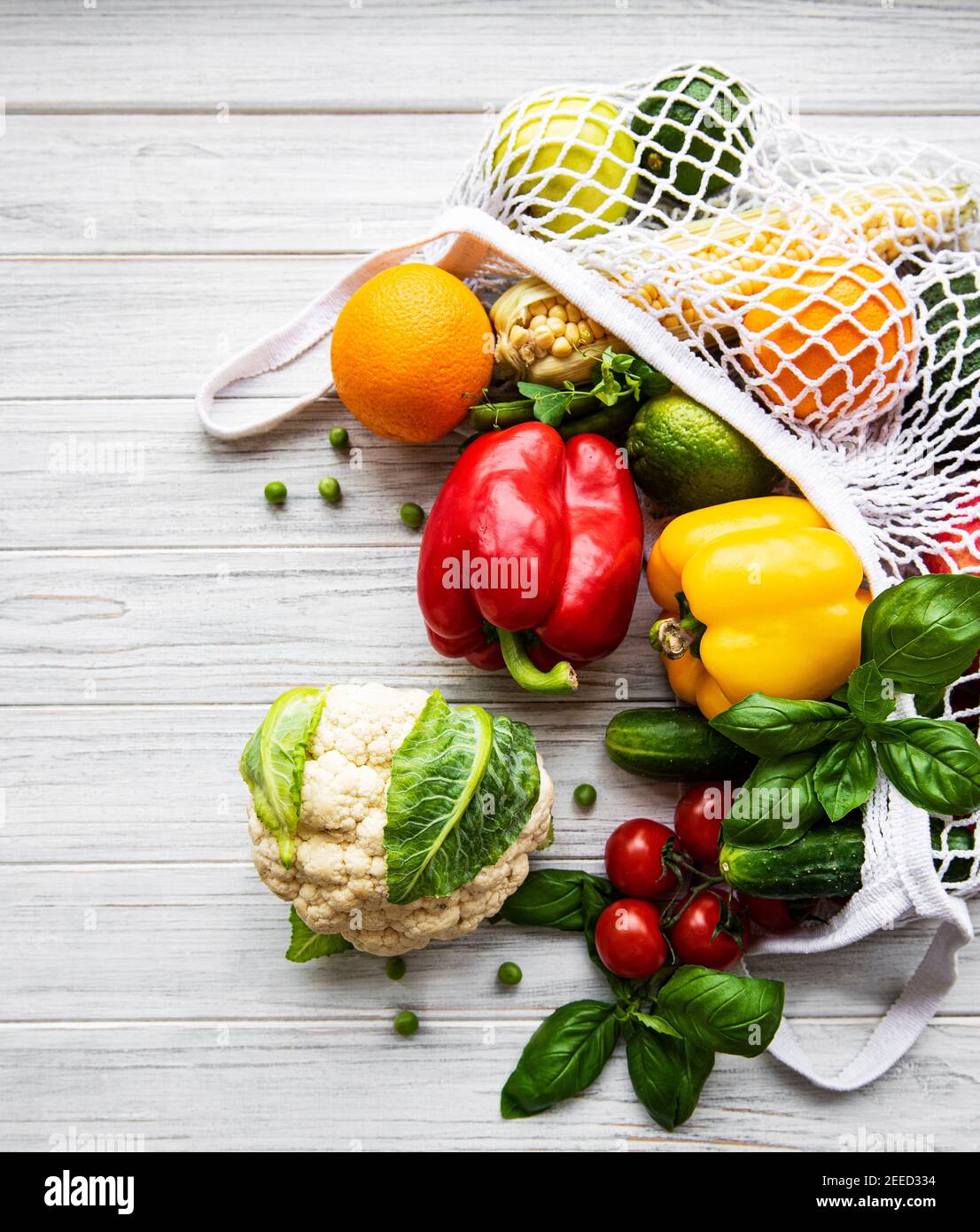 Fresh vegetables and fruits on eco string bag on a white wooden ...