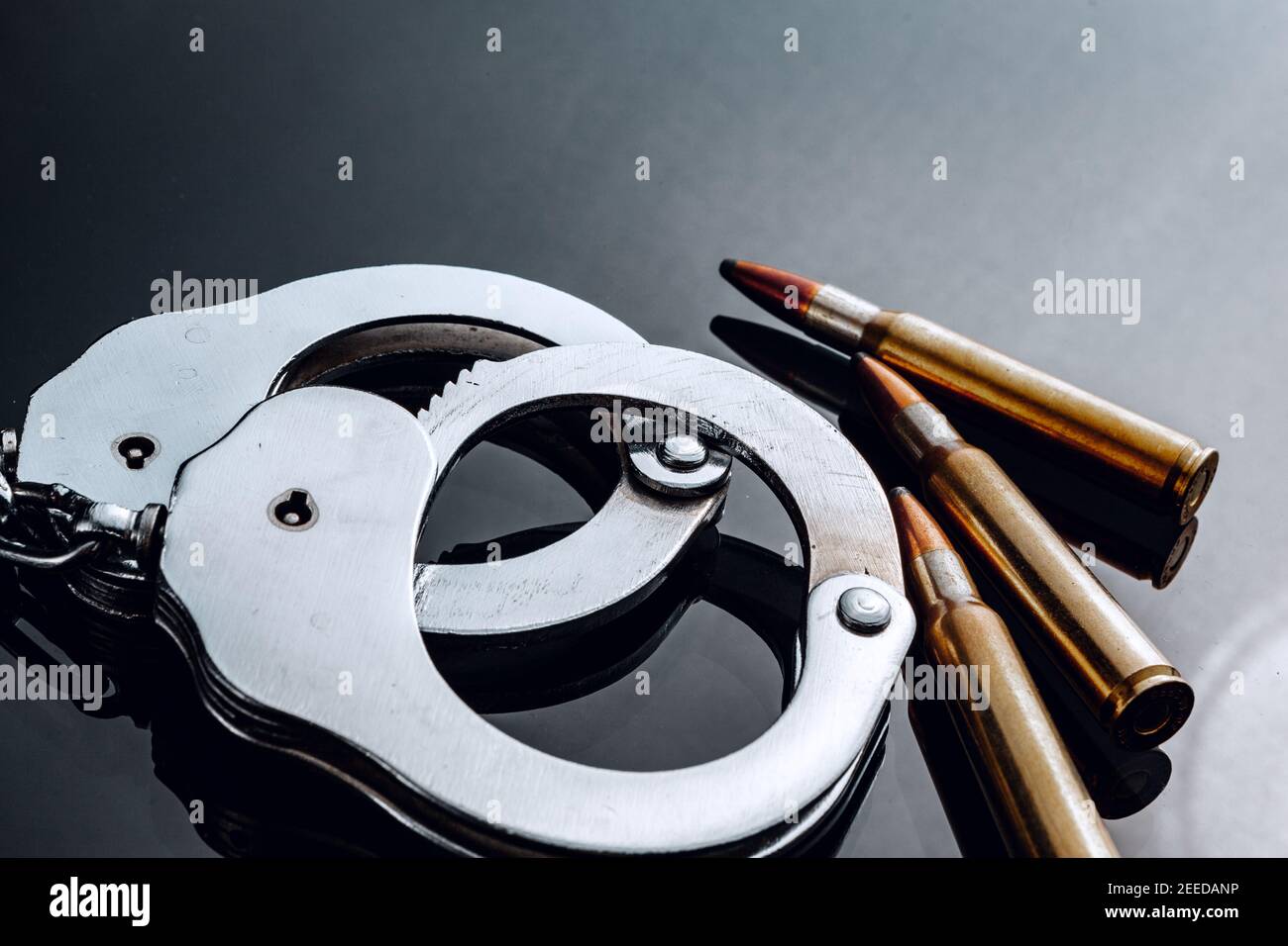 Handcuffs and rifle bullets on black background Stock Photo - Alamy