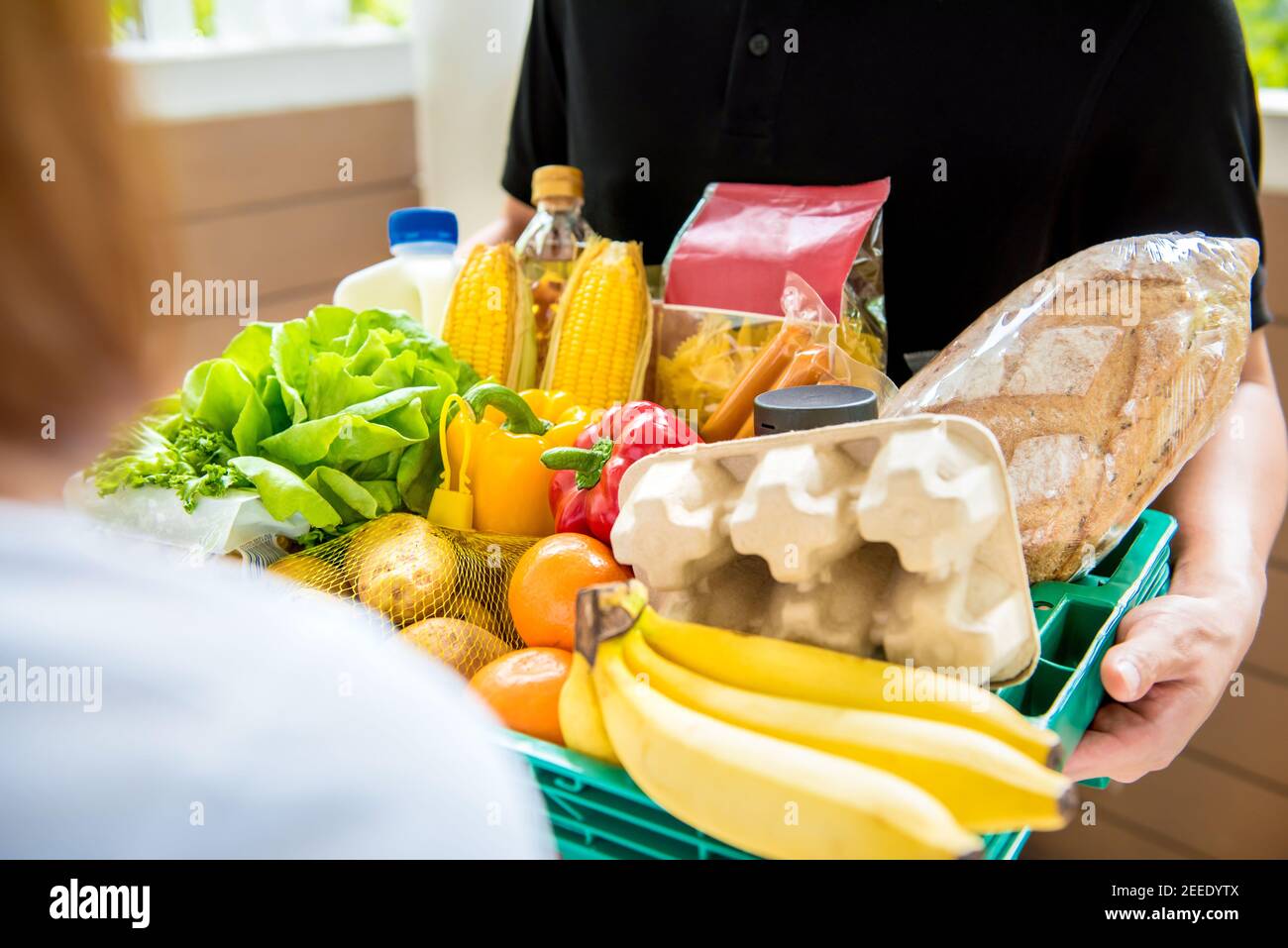 Delivery man in black uniform delivering food to customer at home ...
