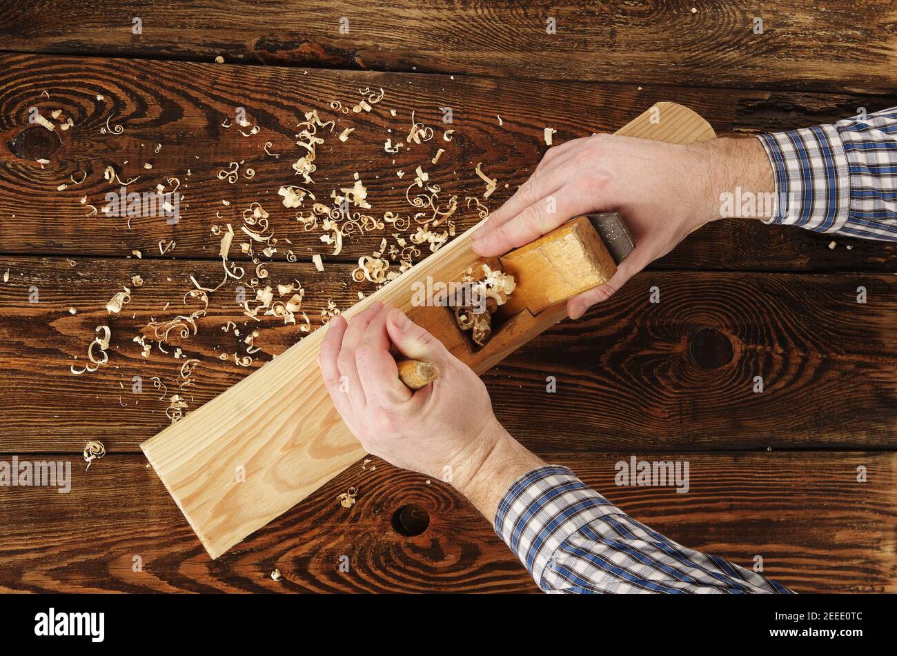 carpenter planes a workpiece on a workbench. view from above. carpenter ...