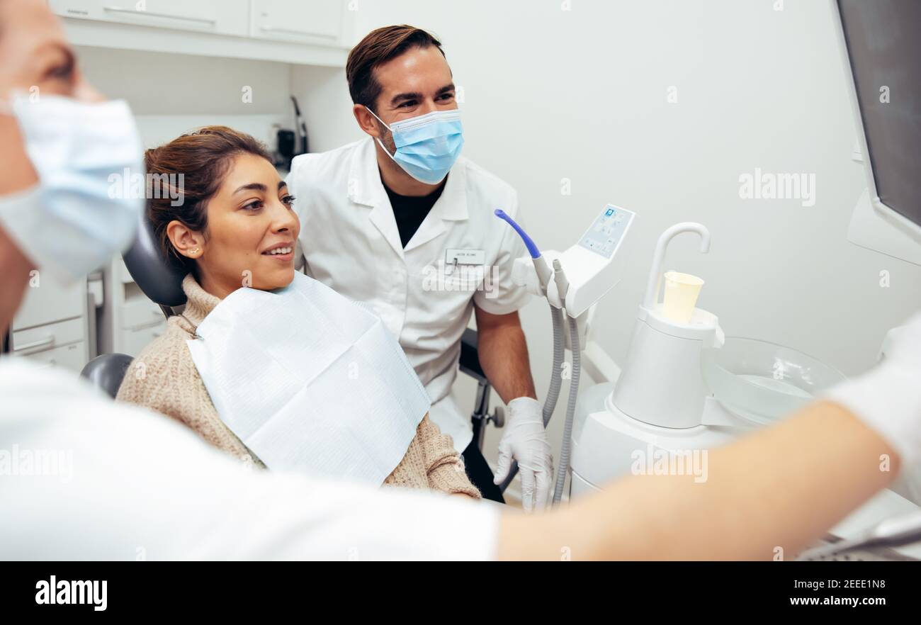 Woman sitting in dentist's chair looking at her dental x-ray with ...