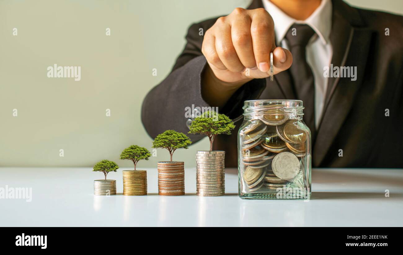 Planting a tree on a pile of money and businessman, man saving money ...