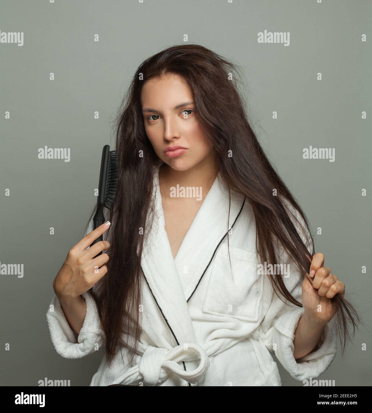 Sad woman combing her tangled hair on white background, hair care and ...