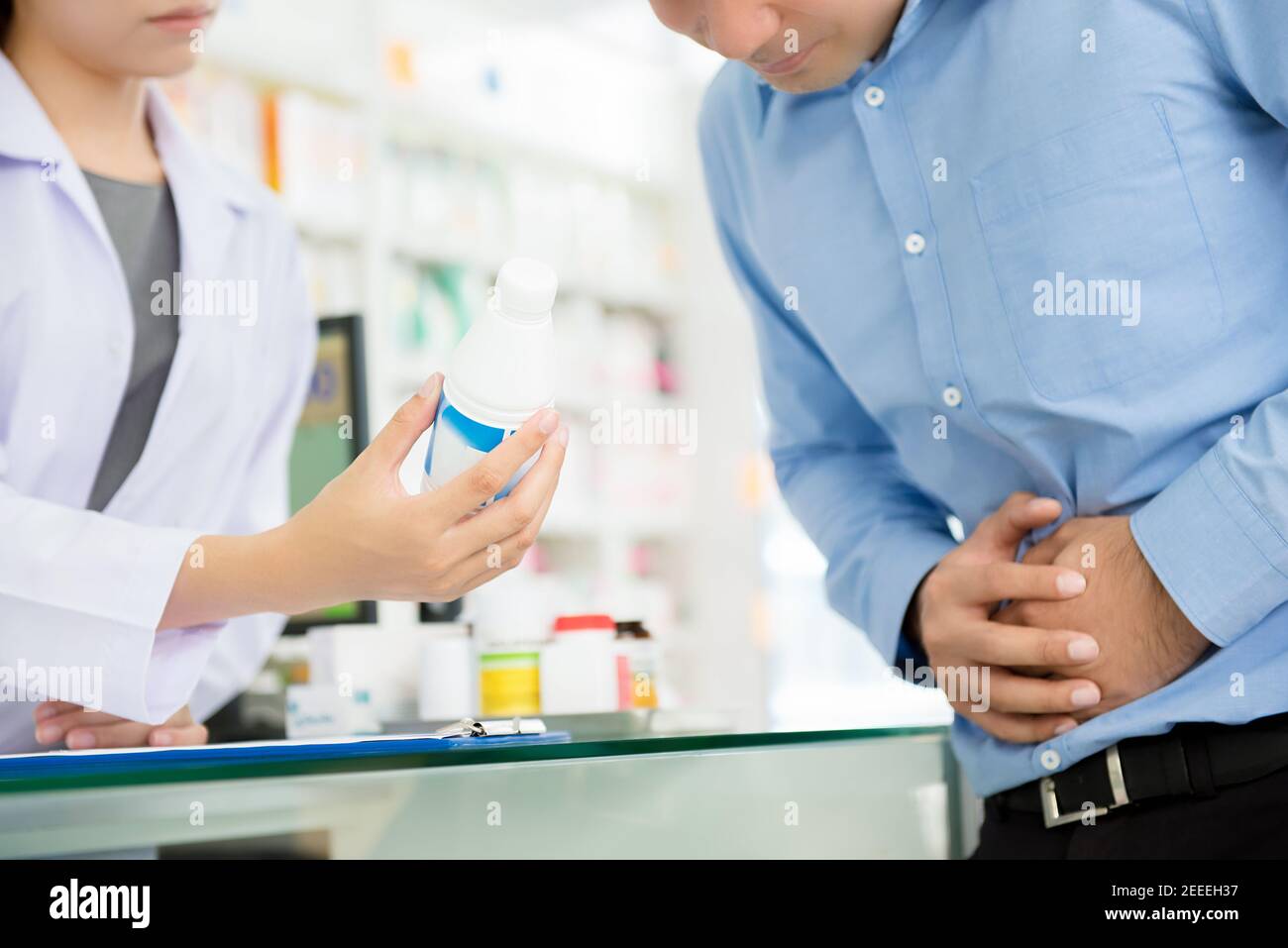 Male patient having stomach pain, consulting with pharmacist in ...