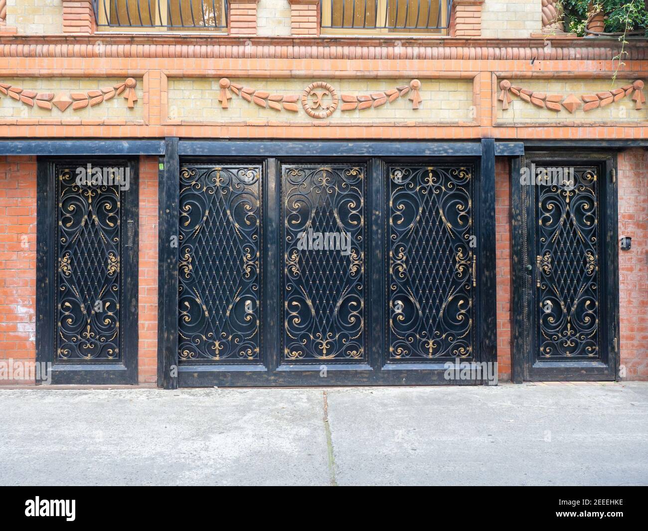 Black iron garage gates and doors with elaborate gilded pattern of ...