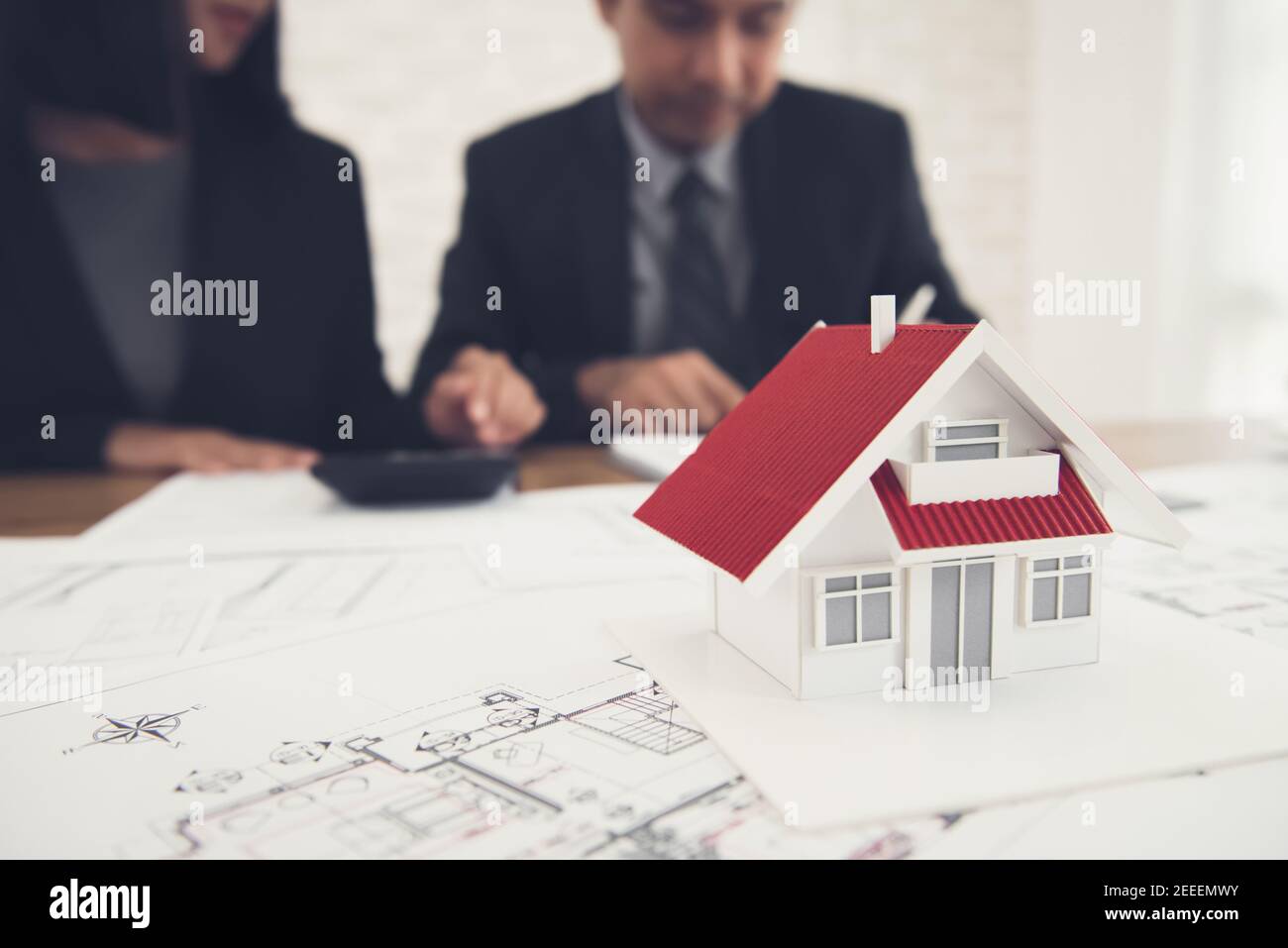 Real estate agent discussing work with blueprints and house model on ...