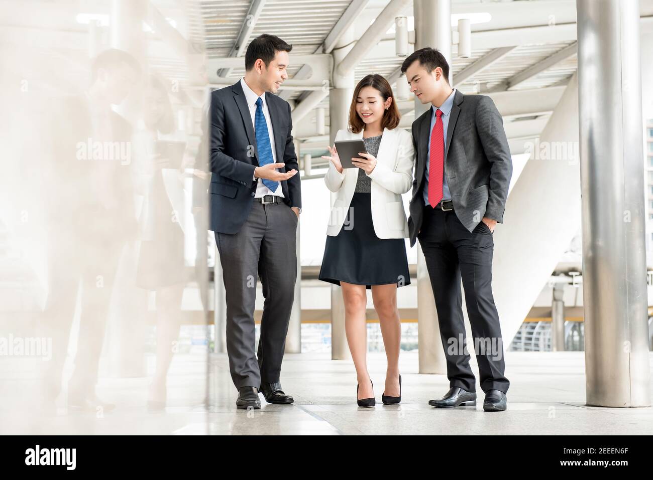 Group of business people talking and looking at tablet computer while ...