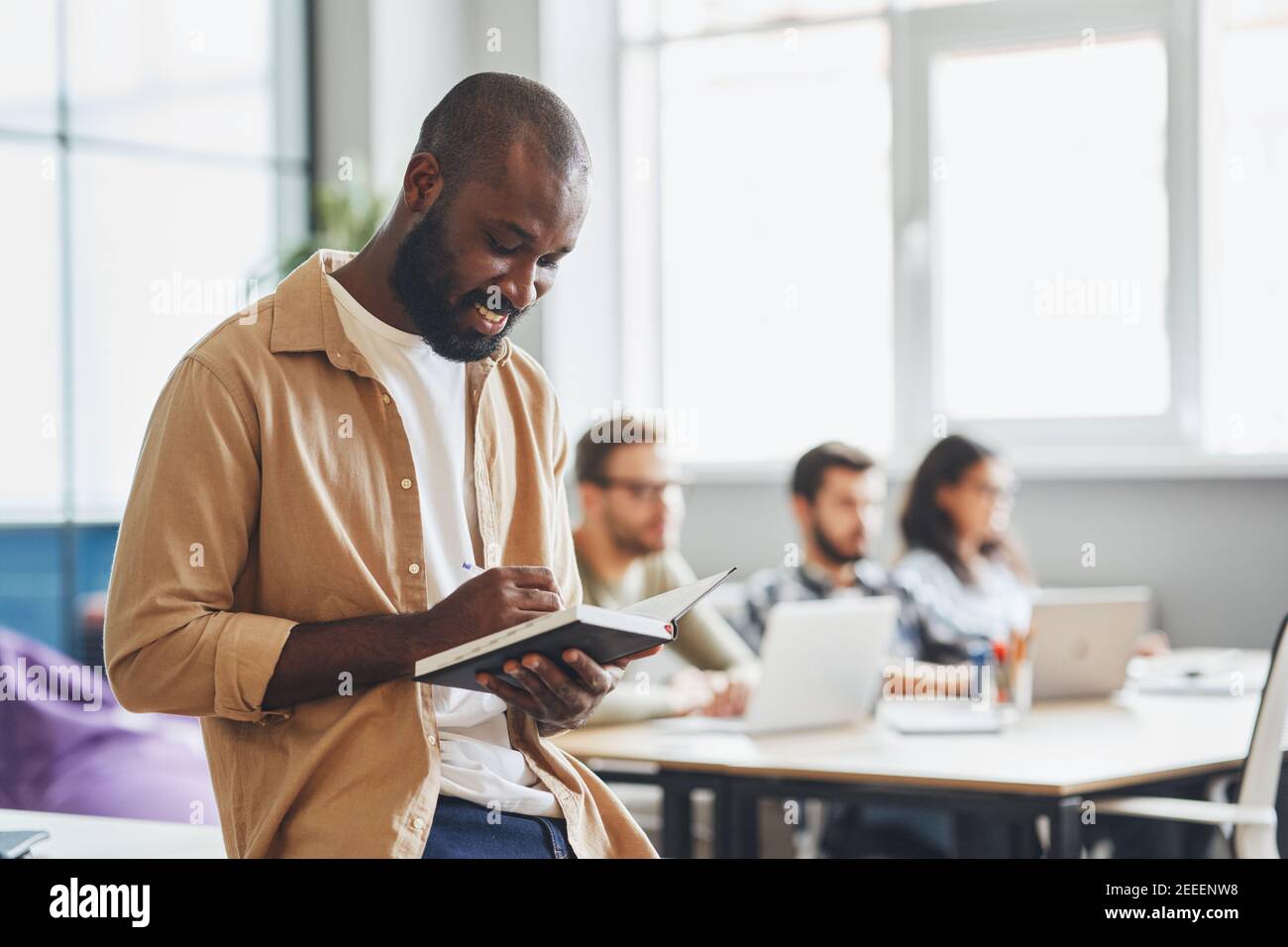 Gladsome young man writing in his note-pad Stock Photo - Alamy